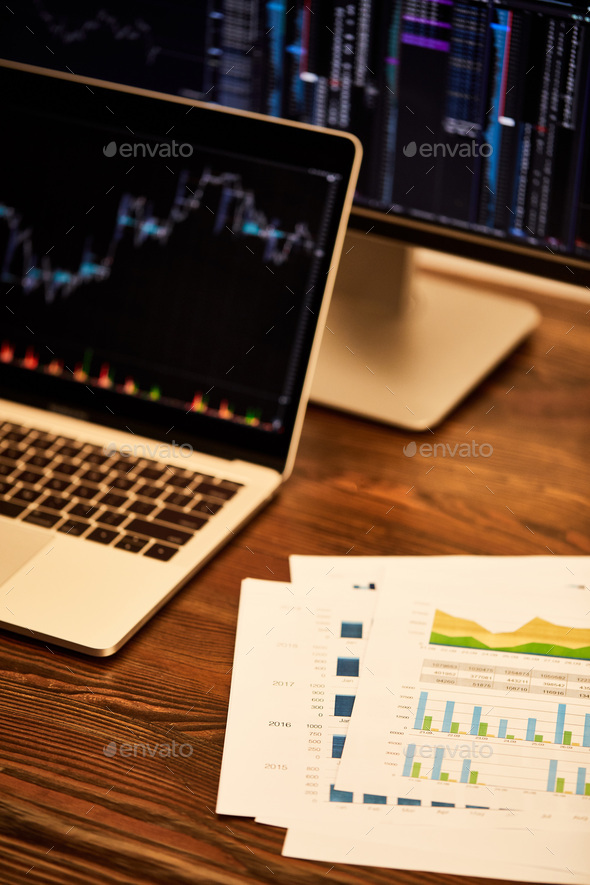 laptop and computer with charts and graphs, documents on table Stock ...