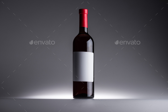 bottle of red wine and blank label on dark background with back light ...