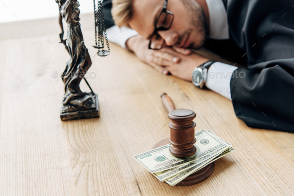 selective focus of tired judge in glasses sleeping on table near gavel ...