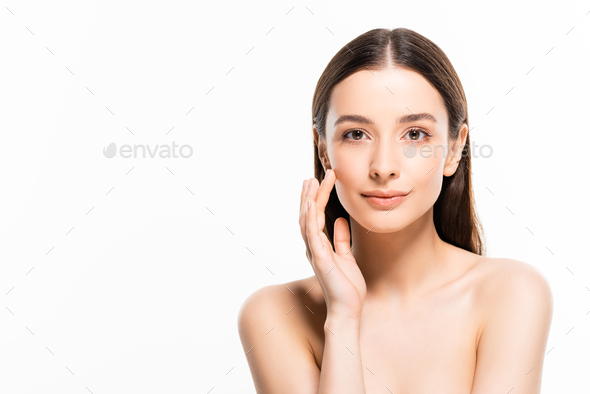 beautiful young naked woman with perfect skin looking at camera while touching face isolated on ...
