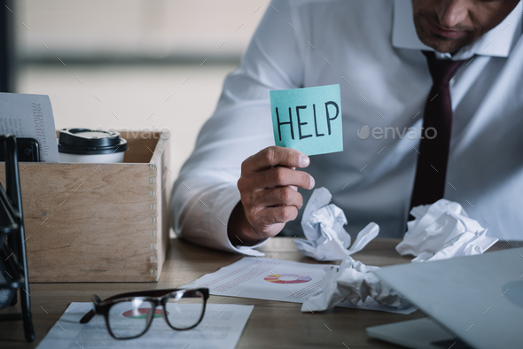 cropped view of upset businessman holding sticky note with help ...