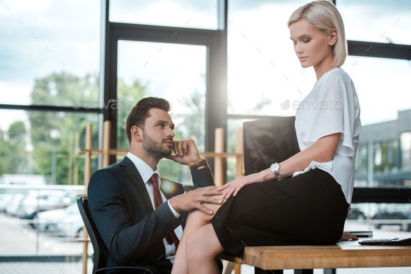 handsome man touching leg of attractive girl sitting on table Stock ...
