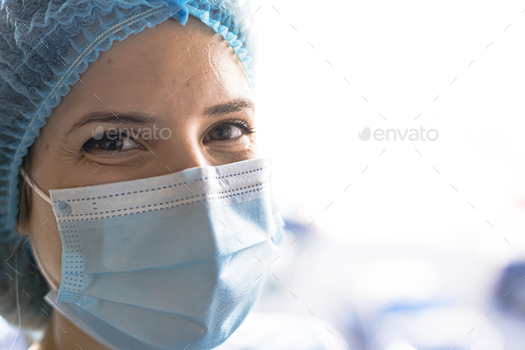 Portrait of a female medical doctor wearing a face mask and cap for ...