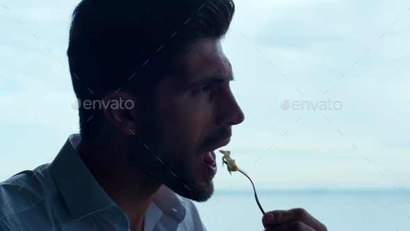 Handsome guy eating healthy dinner in modern outdoor restaurant alone ...