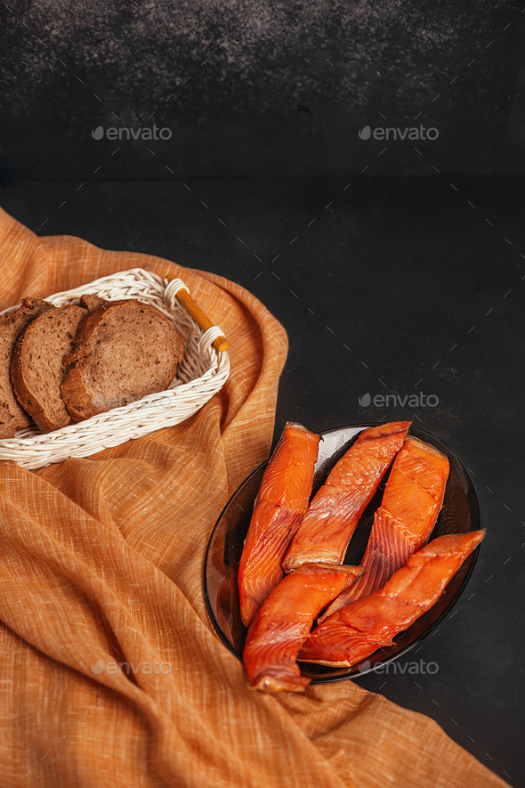 smoked red fish slices on a dark background with bread, minimalism in ...