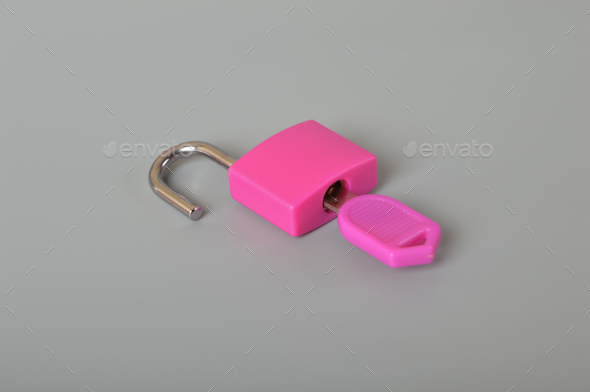 Pink padlock and key isolated on a grey background. Copy space for the ...