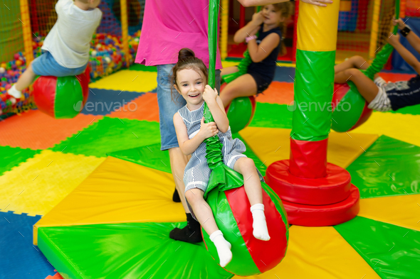 Girl rides on a carousel in a children's play center Stock Photo by ...