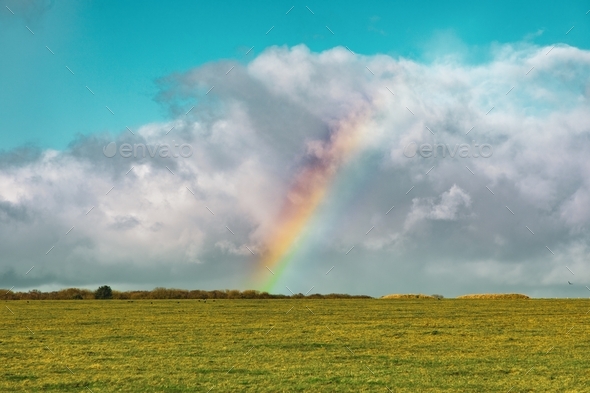 Beautiful shot of an empty grassy field with a rainbow in the distance ...