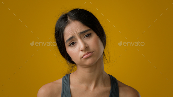 Sad upset worried Indian woman girl in yellow studio background ...