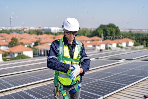 Engineer on rooftop stand next to solar panels wear safety gear wear ...