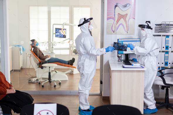 Dental receptionist dressed in coverall giving doctor patient x-ray ...