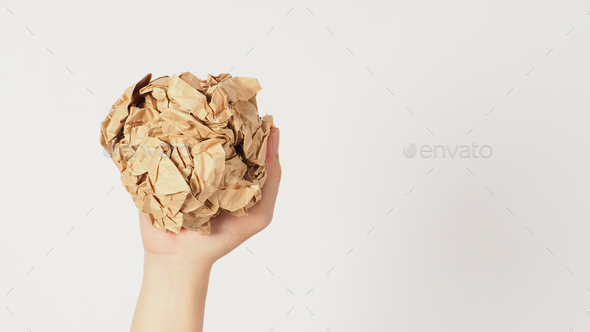 The man's hand is holding crumpled brown paper ball on white background ...