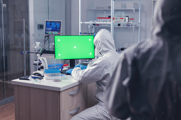 Scientist dressed in ppe suit working on computer Stock Photo by DC_Studio
