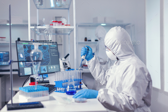 Engineer in microbiology lab holding micropipette Stock Photo by DC_Studio