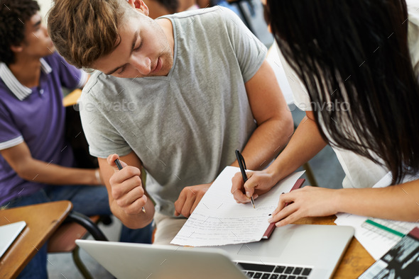 Study partners. A young male and female student studying in a classroom ...