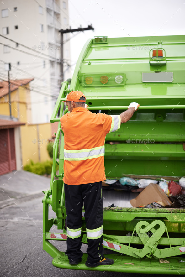 Onward. A garbage collection worker riding on the back of a garbage ...