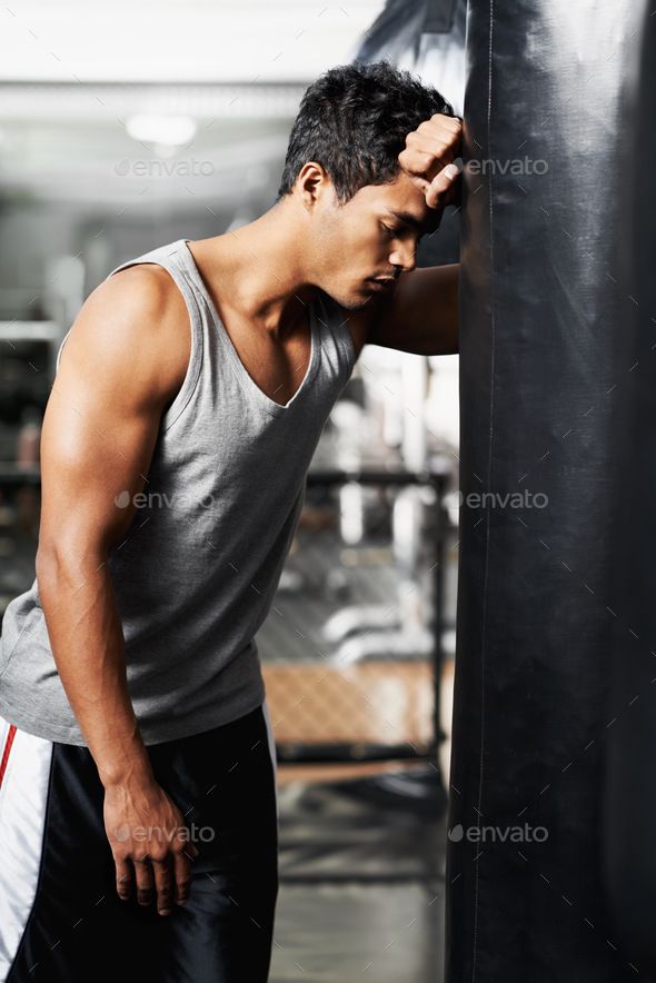 Exhausted after a workout. A muscular young man leaning against a ...