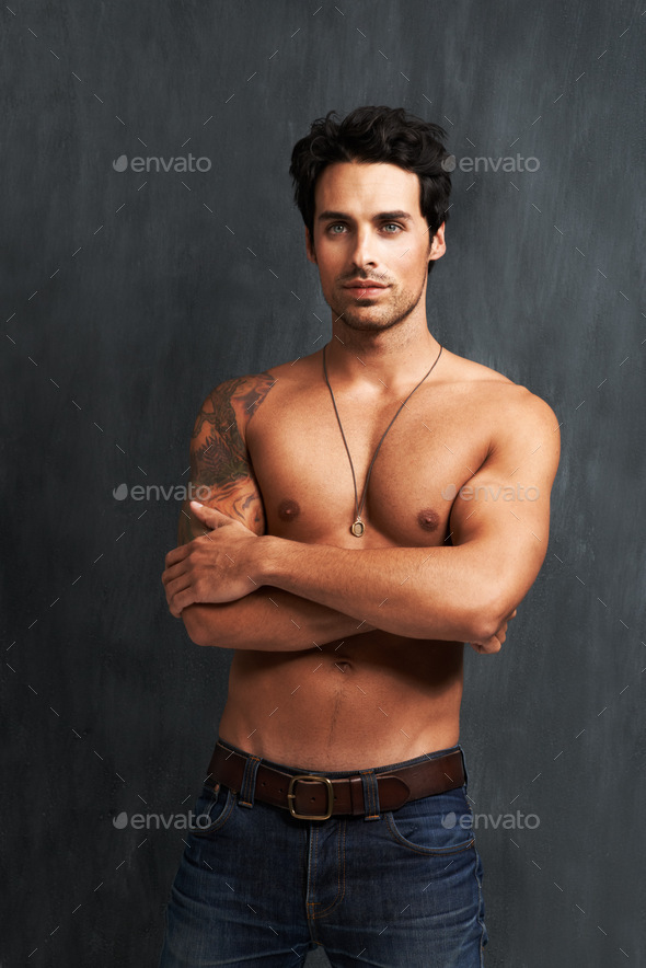 Confident and buff. A shirtless young man standing with his arms folded ...