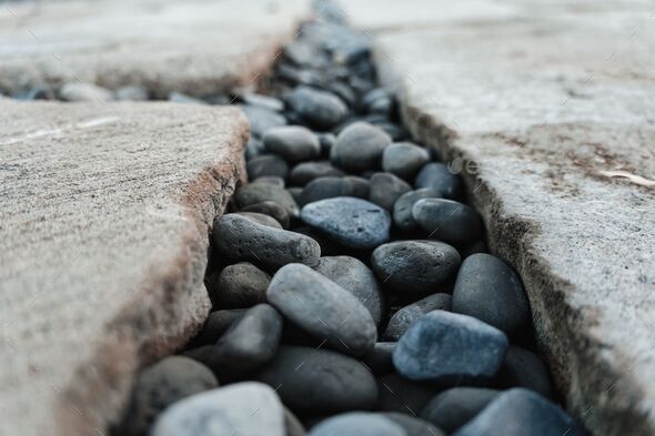 Stack of rocks in between concrete pavers Stock Photo by wirestock
