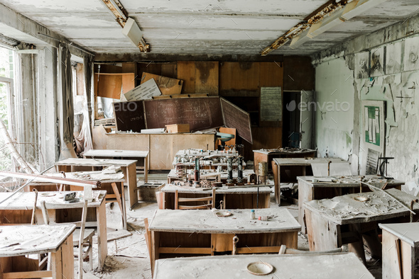 abandoned and creepy classroom with dirty tables and chalk board in ...