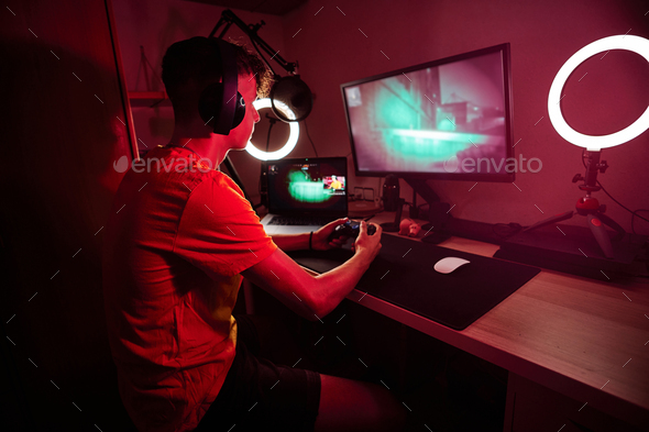 Gamer playing with a console and a computer screen indoors Stock Photo ...