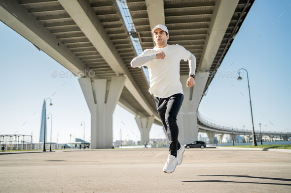 Athlete fast running man conducts fitness training on the street in the ...