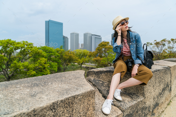 female posing on rock in osaka castle park Stock Photo by primagefactory