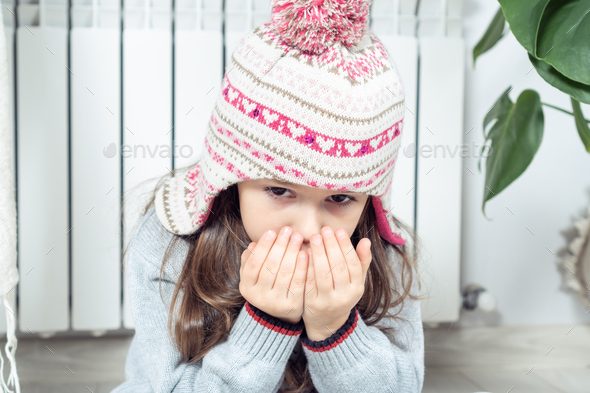 Close up little brunette girl face breathing on hands to keep warm near ...