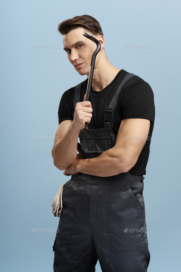 Serious male builder holding crowbar isolated on blue background Stock ...