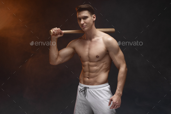 Waist up portrait view of muscle man posing in studio with baseball bat ...