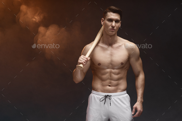Close-up portrait of muscular man posing with bat at studio alone Stock ...