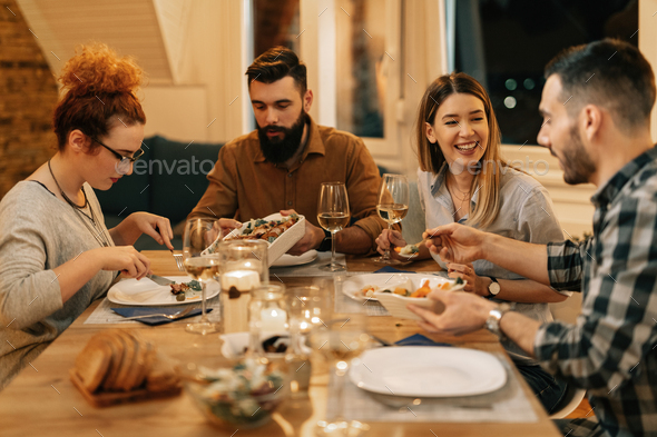 Group of happy friends talking and eating sinner at dining table. Stock ...