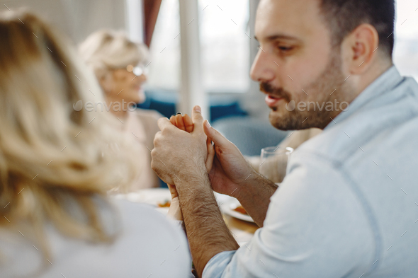 Close-up of couple holding hands while talking at dining table. Stock ...