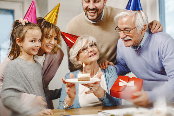 Happy extended family celebrating mature woman's Birthday at home ...