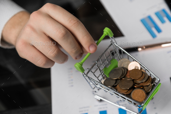 man's hand holds a Dummy shopping cart filled with coins Stock Photo by ...