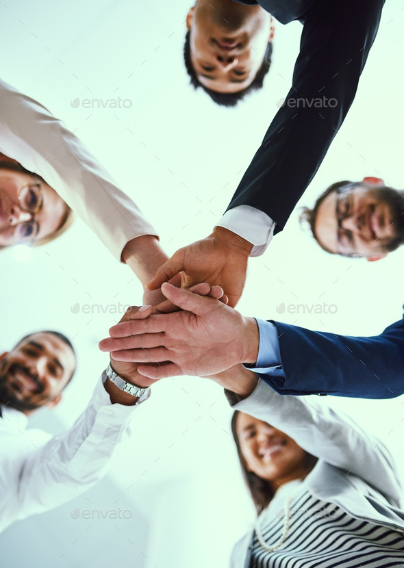 Low angle shot of a diverse group of businesspeople joining their hands together in unity Stock ...