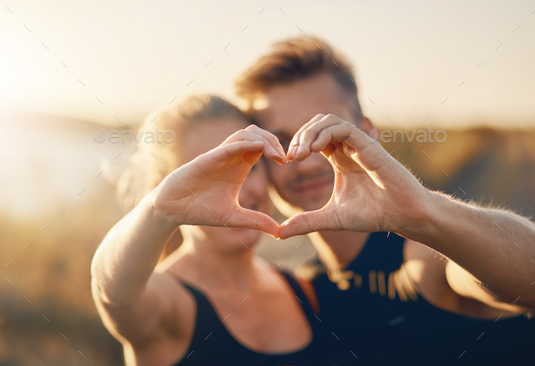 Shot of a young couple making a heart shape with their hands outdoors ...