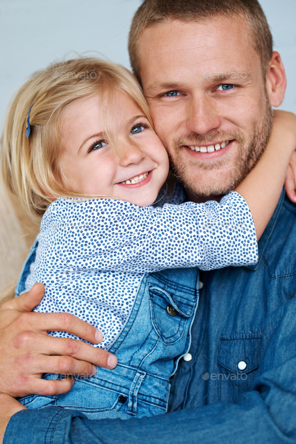 Portrait of an adorable little girl hugging her father around the neck ...