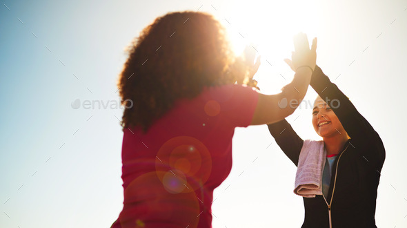 Low angle shot of two cheerful young friends exchanging high fives ...