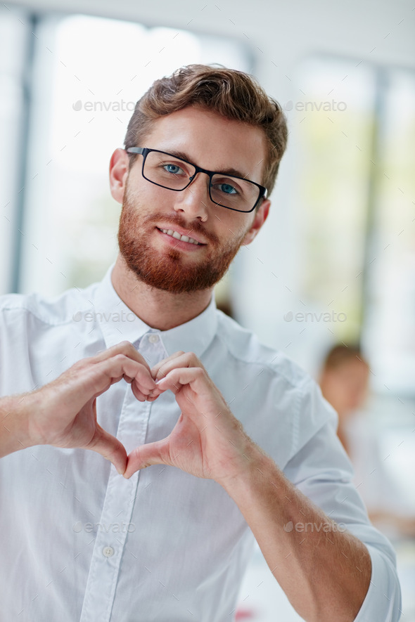 Portrait of a businessman making a heart shape with his hands over his ...