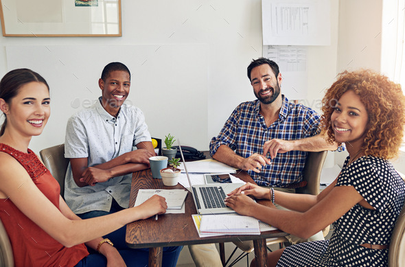 Portrait of a group of colleagues working together at a desk in an ...