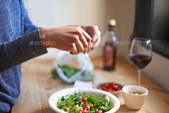 Creating the perfect lunch. A young woman making a salad in her kitchen ...