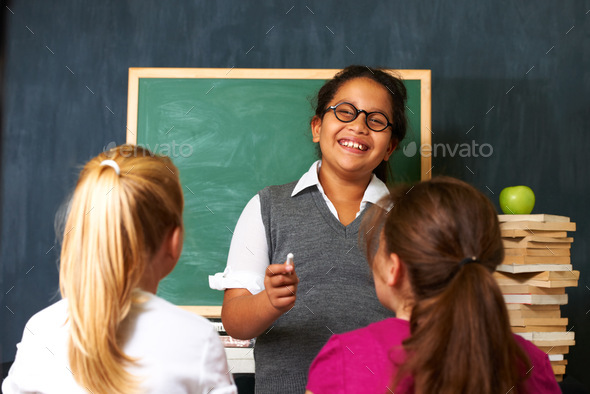 Portrait of a cute girl teaching her two classmates something using the ...