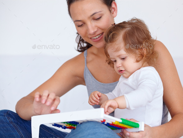 Learning is fun. A cute baby girl being taught by her mother how to use ...