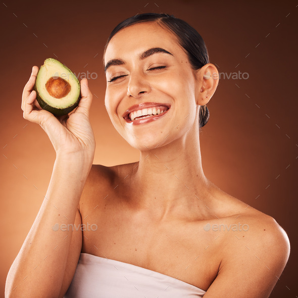 Face, skincare and avocado with a model woman in studio on a brown ...