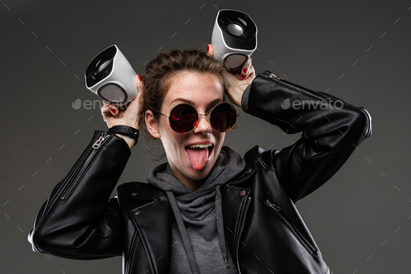 A young girl with rough facial features in a black jacket listens to ...