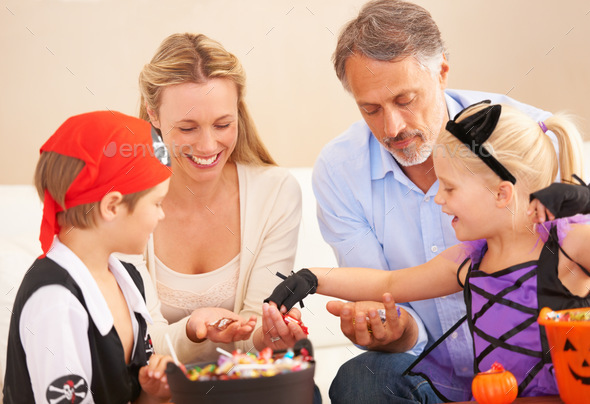 A family sitting together and sharing sweets on halloween with children ...