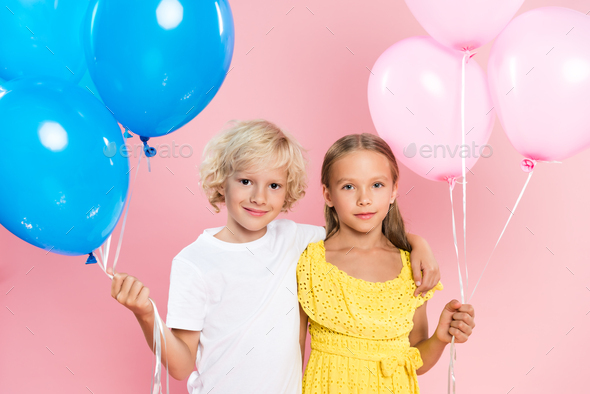 smiling and cute kids hugging and holding balloons on pink background ...