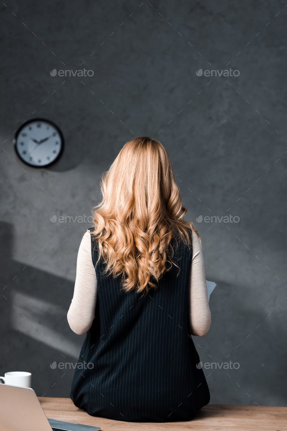 back view of blonde businesswoman sitting on table in office Stock ...