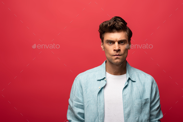 portrait of handsome angry man in casual clothes isolated on red Stock ...